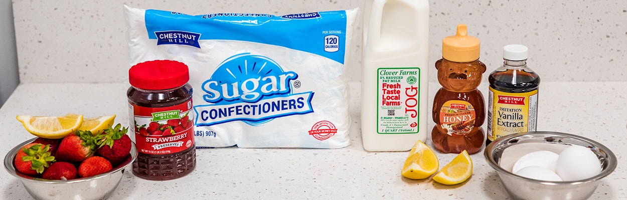 A bowl of strawberries and lemons next to strawberry preserves ...